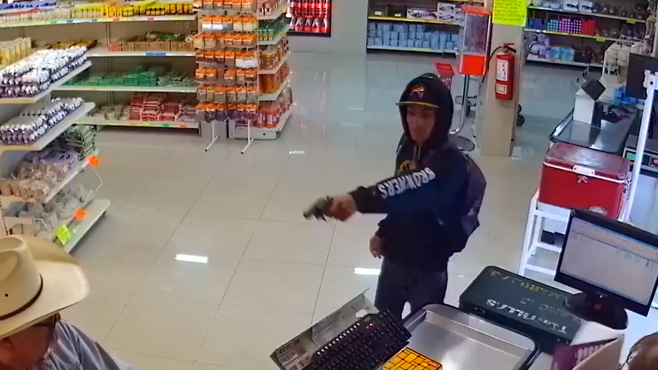 Man in cowboy hat wrestles gun away from man holding up butcher's shop ...